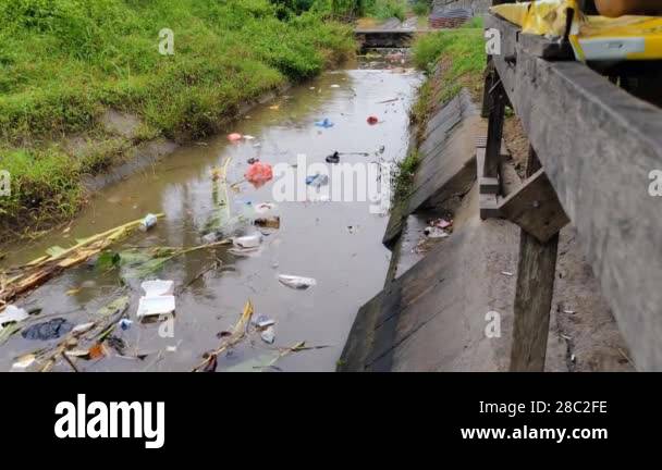 a small dirty polluted river carries away a lot of garbage in the rainy ...