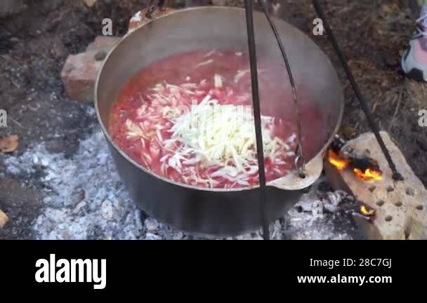 Cook red Ukrainian borscht over a campfire while hiking. Cooking food ...