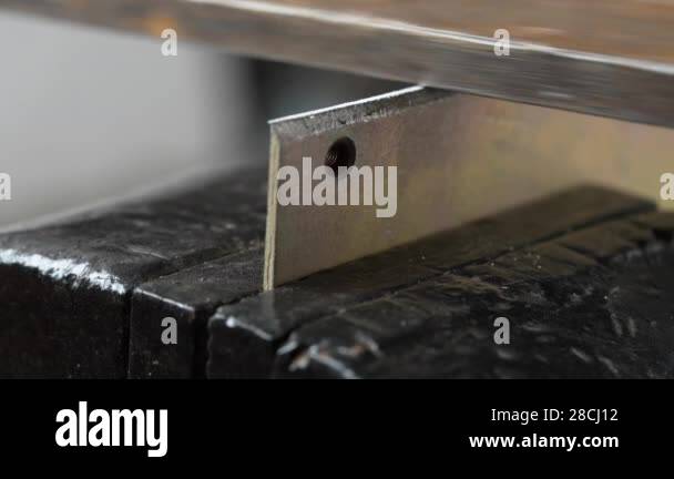 Craftsman works on small piece of metal with metal file gripped in vise ...