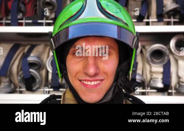 Young smiling fireman looking at camera in full equipment after fire ...