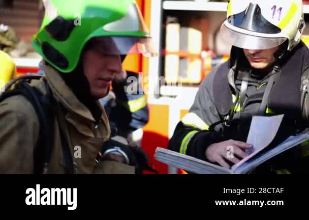 Male firefighters in protective uniforms discuss rescue plan looking at ...