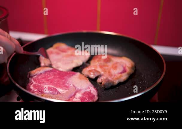Several lean pork chops being fried in a very hot pan. over open blue ...