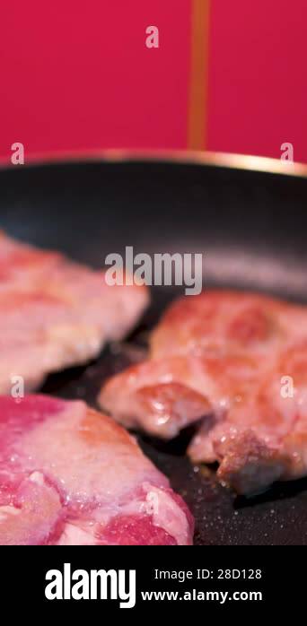 Several lean pork chops being fried in a very hot pan. over open blue ...