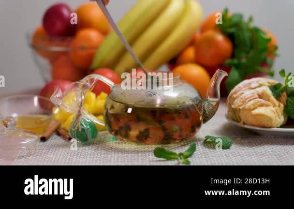 tea stir in a glass teapot close the lid on the table fruits croissant ...