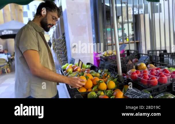 Young man selecting oranges at an outdoor market stall Stock Video ...