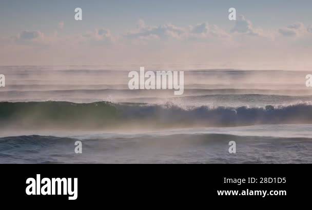 Sea sunrise with mist over rolling waves to the beach shore, beautiful ...