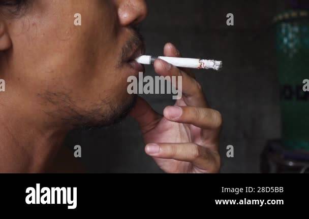 A man smoking a cigarette. It is dangerous to the people around ...