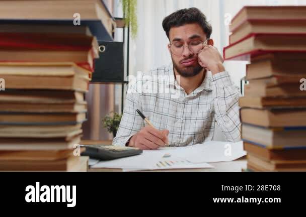 Exhausted Indian businessman reviewing documents reports while using ...