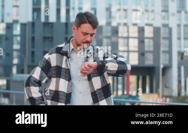 Serious sad businessman standing outside office looking around waiting ...