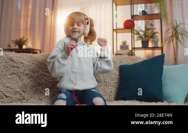 Young teenager girl wears headphones at home dancing, humming a ...