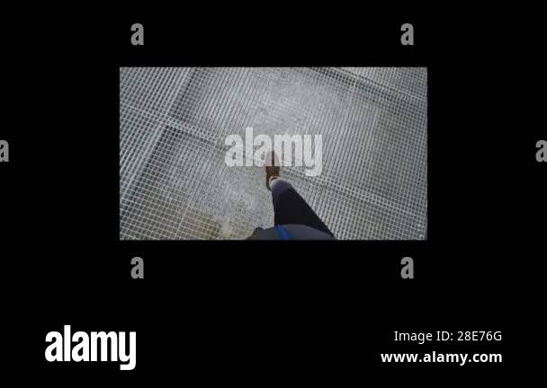 a man walks on a metal grid bridge over a snowy ravine. galvanized ...