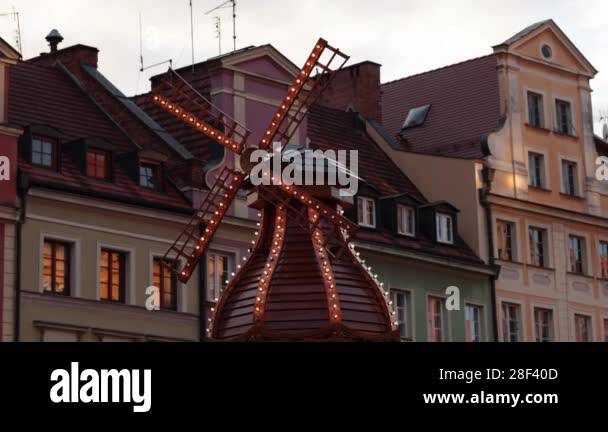 Rotating wooden windmill illuminated with warm festive lights against ...