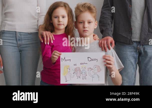 Two children stand together holding a drawing that reflects their ...