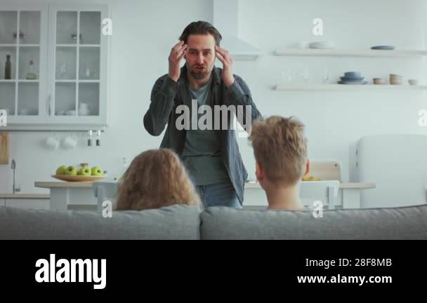 A man appears to confront two children in a modern living room ...