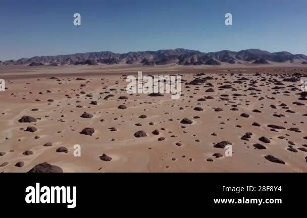 A stunning arid landscape showcases scattered rocks and distant ...