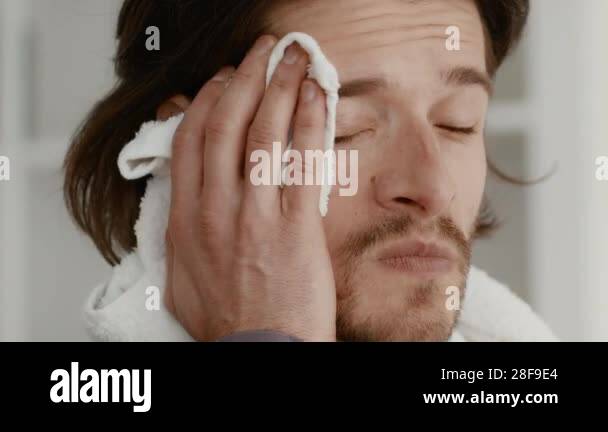 A young Caucasian man takes a moment during his home workout to wipe ...