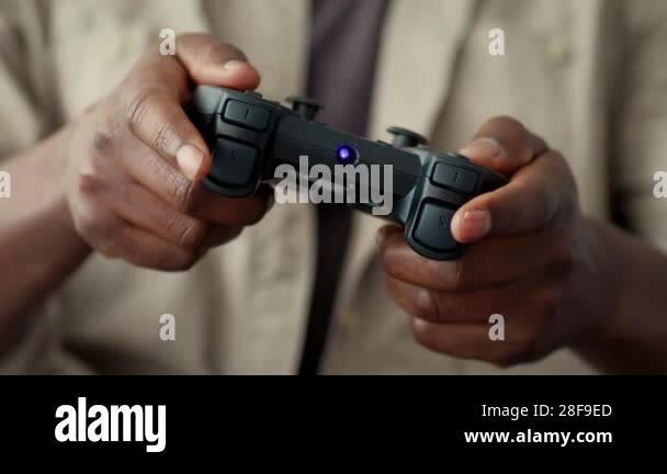 A young African American man focuses on his gaming while holding a ...
