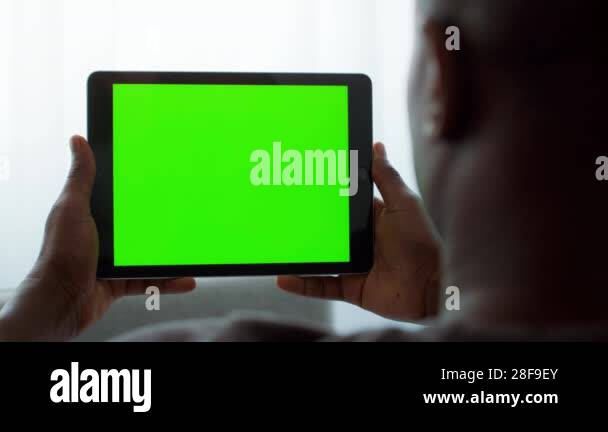 A young African American man sits comfortably at home, focusing on his ...