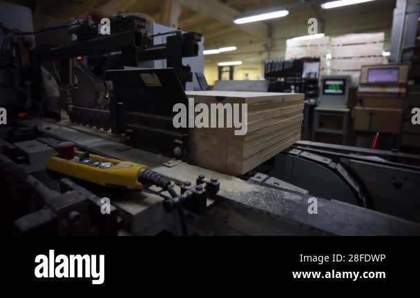 Close up of hands handling wood on a machine in a well lit workshop ...