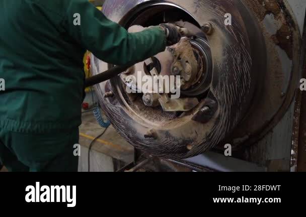 A worker in green protective clothing operates a worn industrial ...