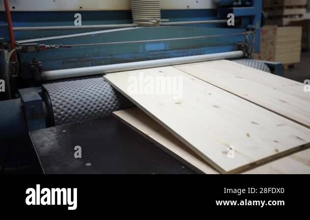 A woodworking machine with a blue frame and metal roller processes ...