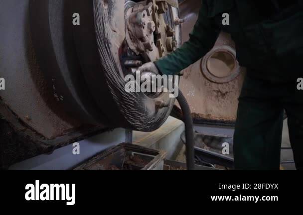 A worker in dark green attire operates a large circular machine with ...