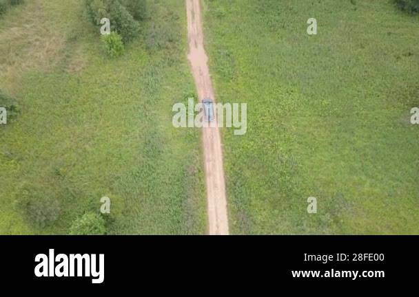An aerial perspective of a dirt road winding through green fields and ...