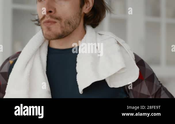 A young Caucasian man engages in a workout at home, showing focus and ...