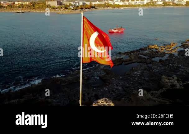 A large Turkish flag is prominent in the foreground, with rocky ...