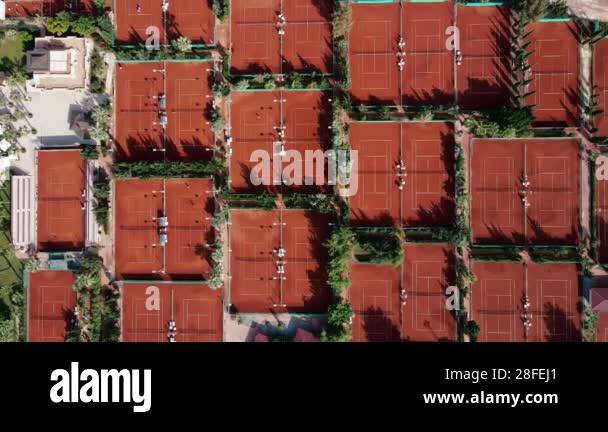 Aerial perspective of multiple red clay tennis courts arranged in a ...