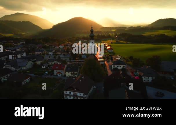 Austrian village at sunset with a central church tower, traditional red ...