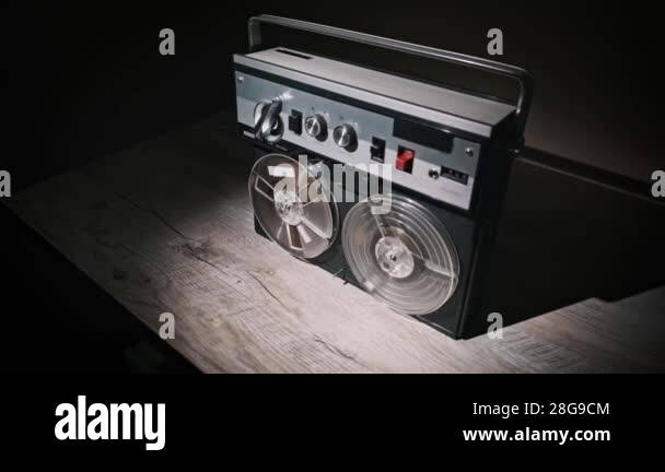 A detailed view of the reels spinning on a vintage tape recorder as it ...