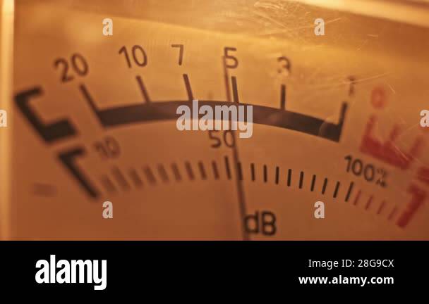 A close-up of a vintage VU meter with a warm golden glow. The analog ...