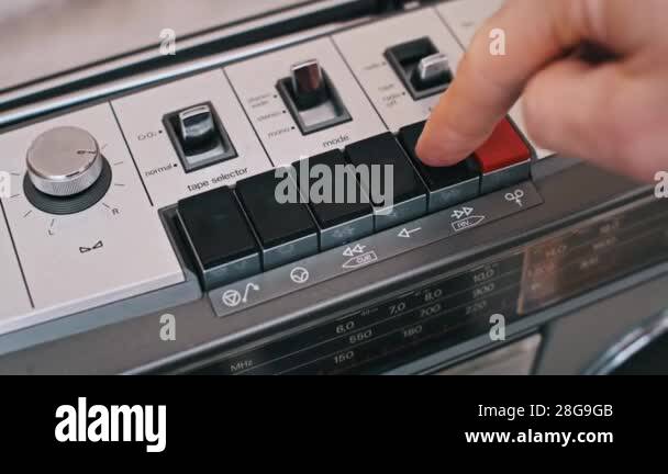 A finger engages the fast-forward button on a retro tape player a close ...