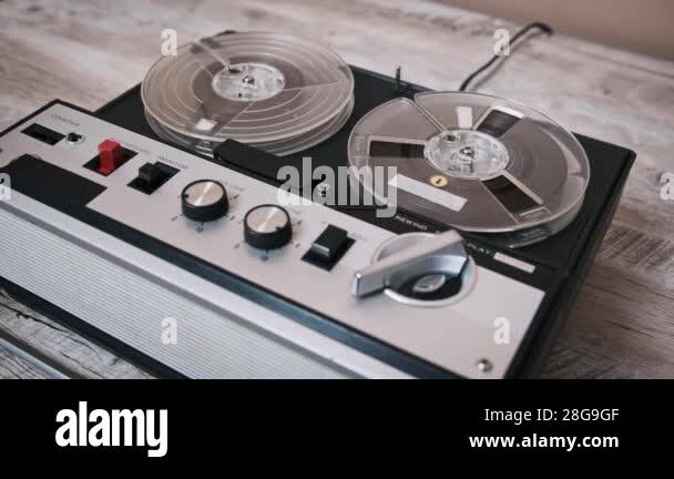 Two transparent reels of tape slowly move on a retro-styled reel-to ...
