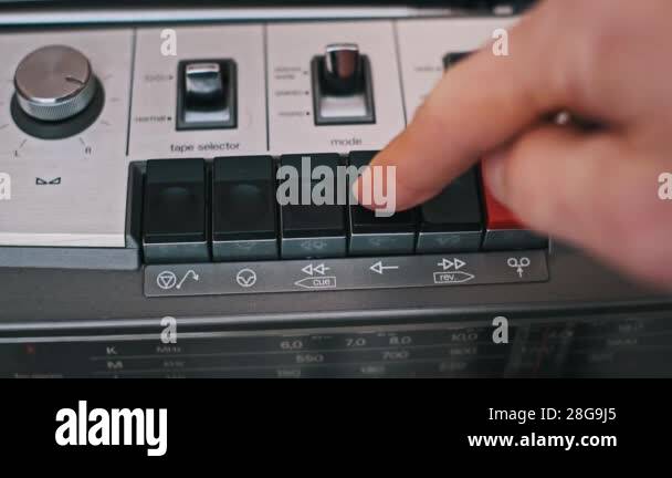 A finger presses the play button on an old-school audio player. Close ...