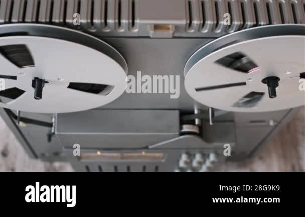 A close-up shot shows the top of a vintage silver reel-to-reel tape ...