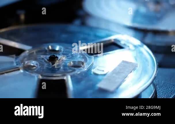 Close up on the rotating reels of a reel-to-reel tape player. Focus on ...