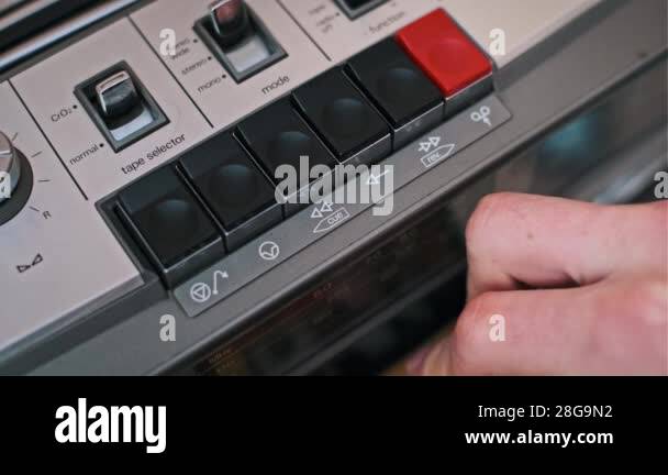 A hand inserts a vintage cassette tape into a retro boombox, then ...