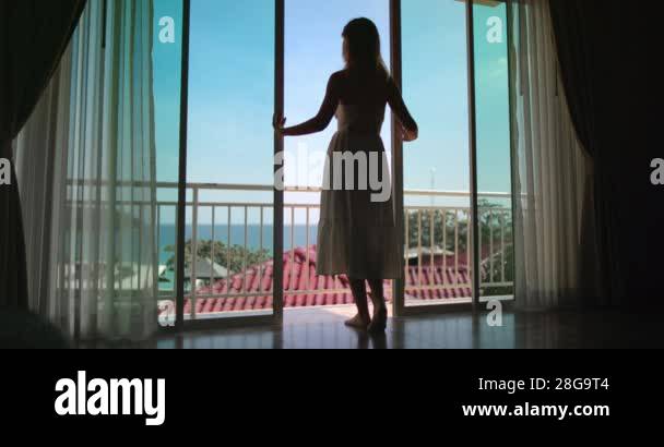 Tourist is entering the terrace of her hotel room enjoying the warm ...