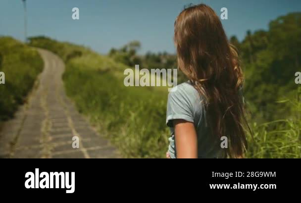 Long hair brunette girl walk green field meadow trail in Ubud, Bali ...