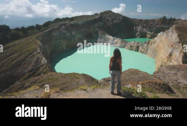 Woman looking on volcano mountain crater edge. Volcanic Kelimutu blue ...