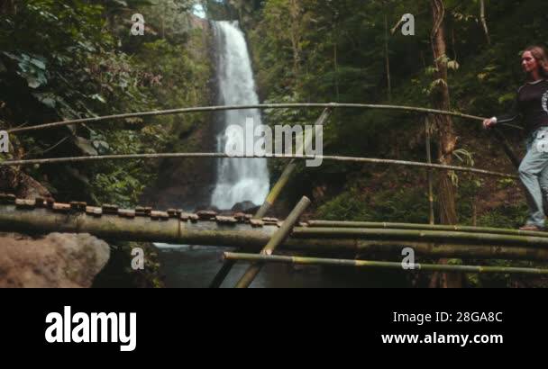 A woman stands confidently on a wooden bridge facing a majestic ...