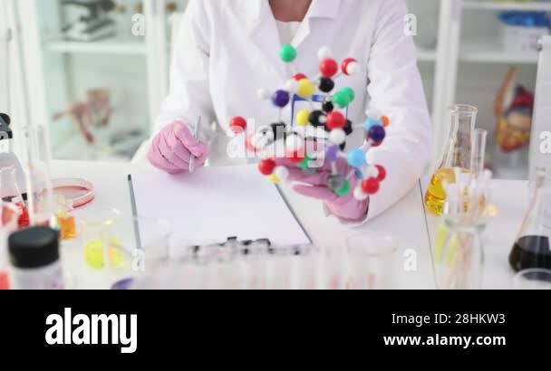 Woman lab technician shows artificial model of molecule. Chemist makes ...