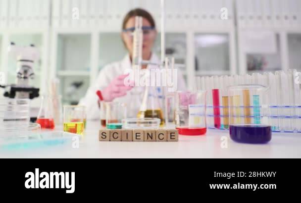 Miniature wooden blocks create word SCIENCE on table. Woman lab worker ...