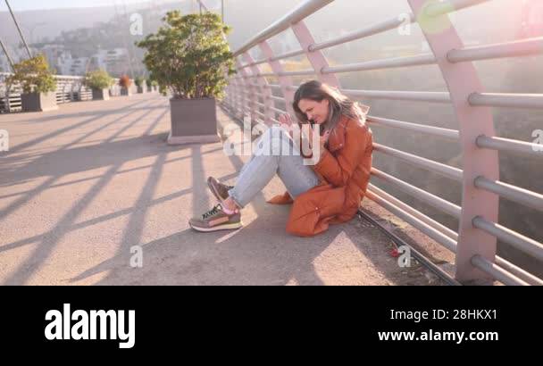 Sad woman sits on pavement of city footbridge experiencing anxiety ...