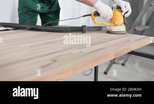 Construction worker polishes wooden board with handheld electric sander ...