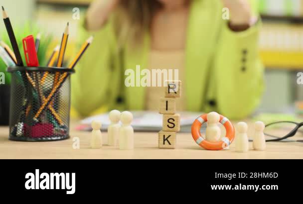 Word Risk from cubes near tiny lifebuoy against woman at workplace in office. Concept of ...