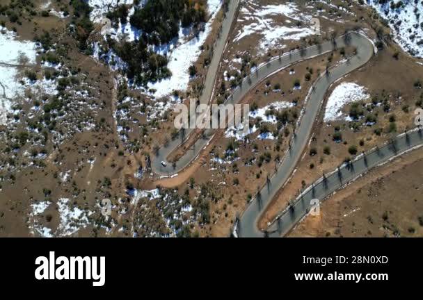 This captivating aerial shot captures a curving mountain road snaking ...