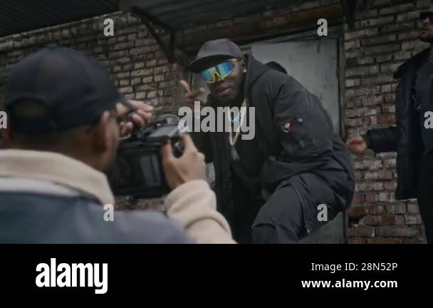 Over shoulder shot of videographer recording male Black rapper singing ...